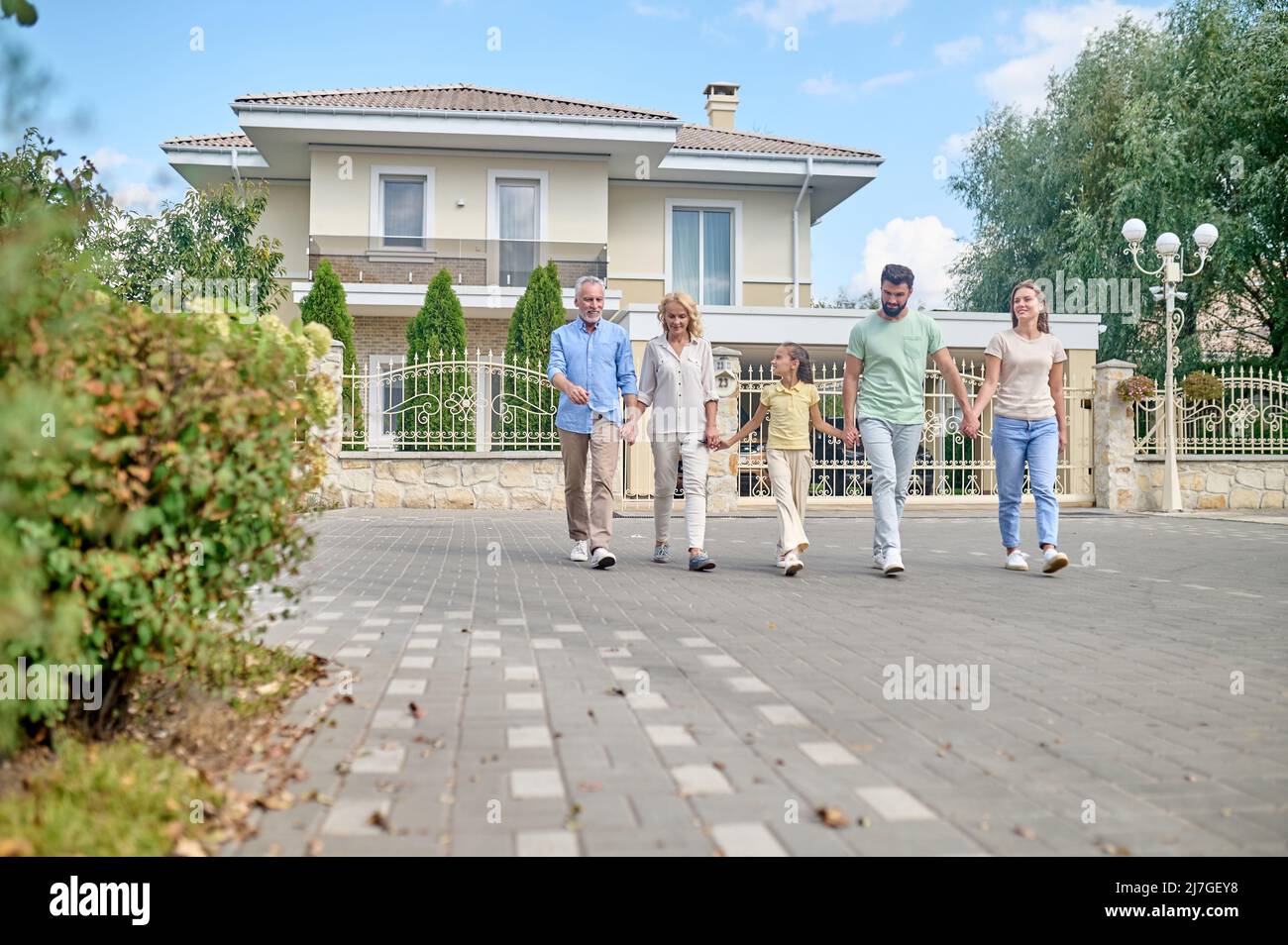 Smiling family walking hand in hand and looking happy Stock Photo - Alamy