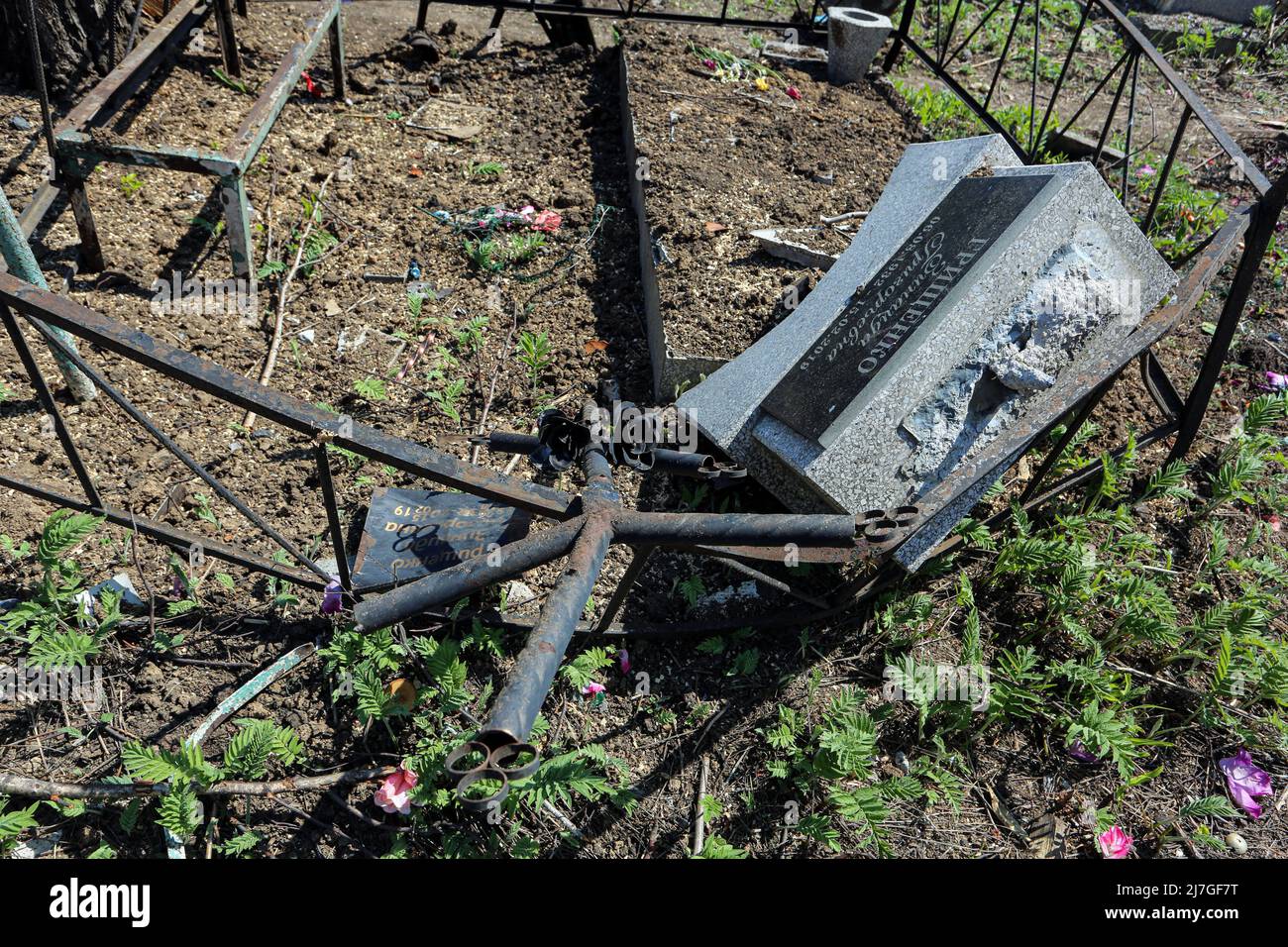 Destroyed fence in the cemetery and the tombstone during the Russia ...