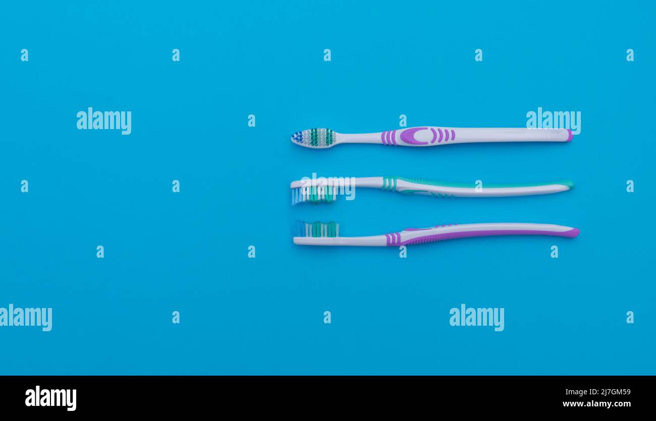three simple toothbrushes for oral hygiene on a light blue background ...