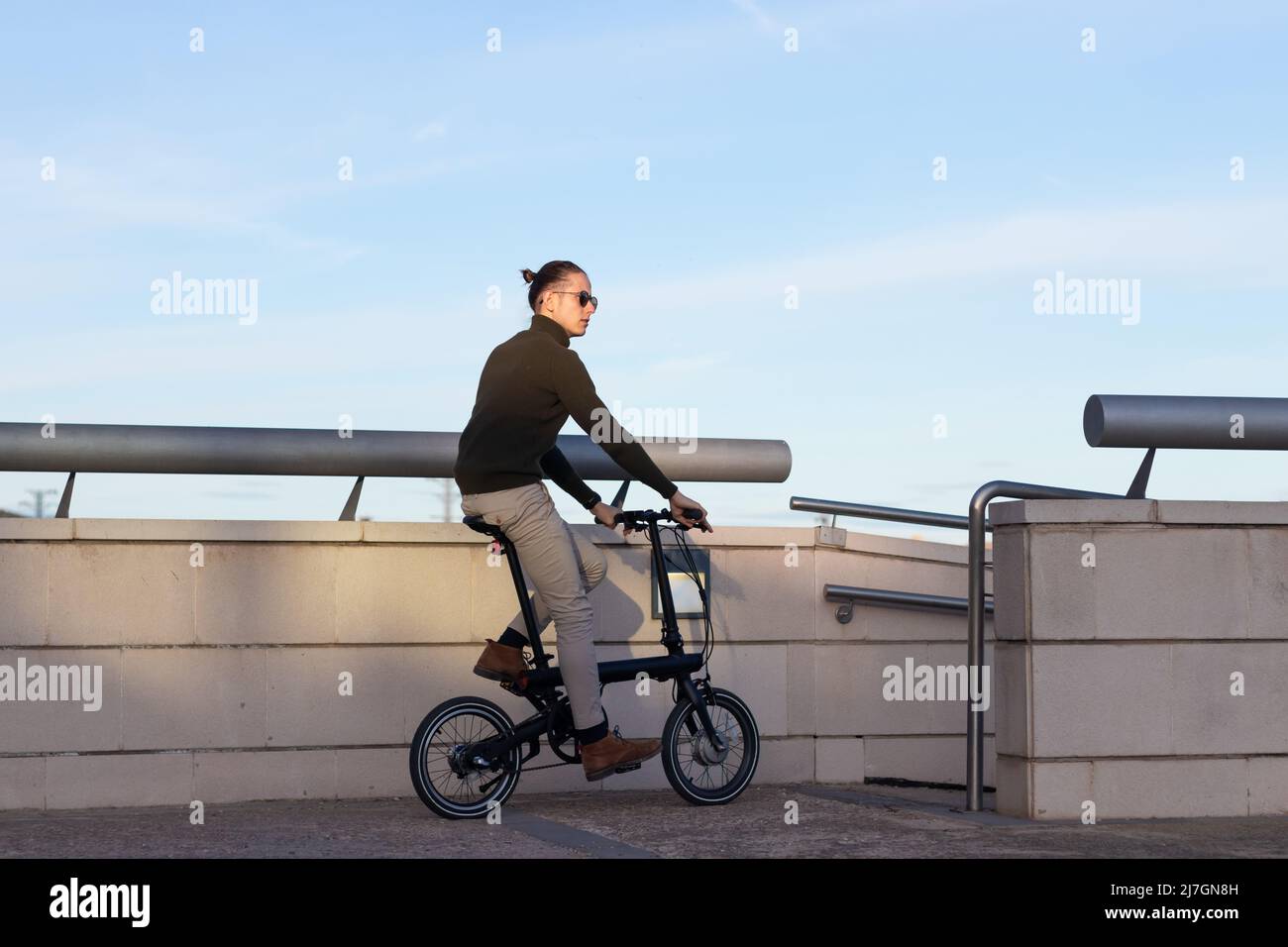 Young man relaxed enjoying a bike ride around the city as a tourist ...