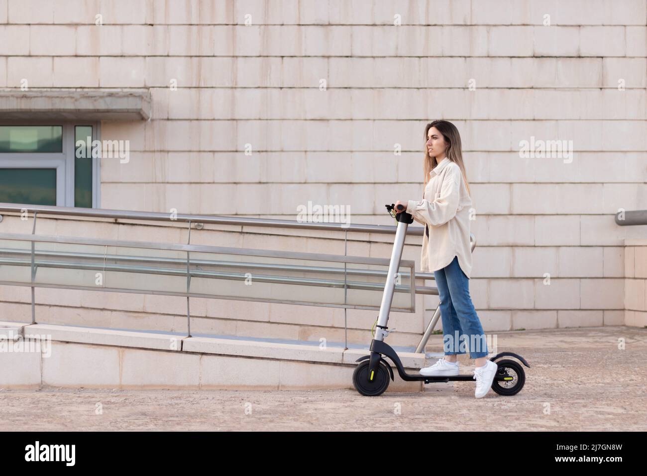 Side view of young woman riding an electric scooter as an alternative ...