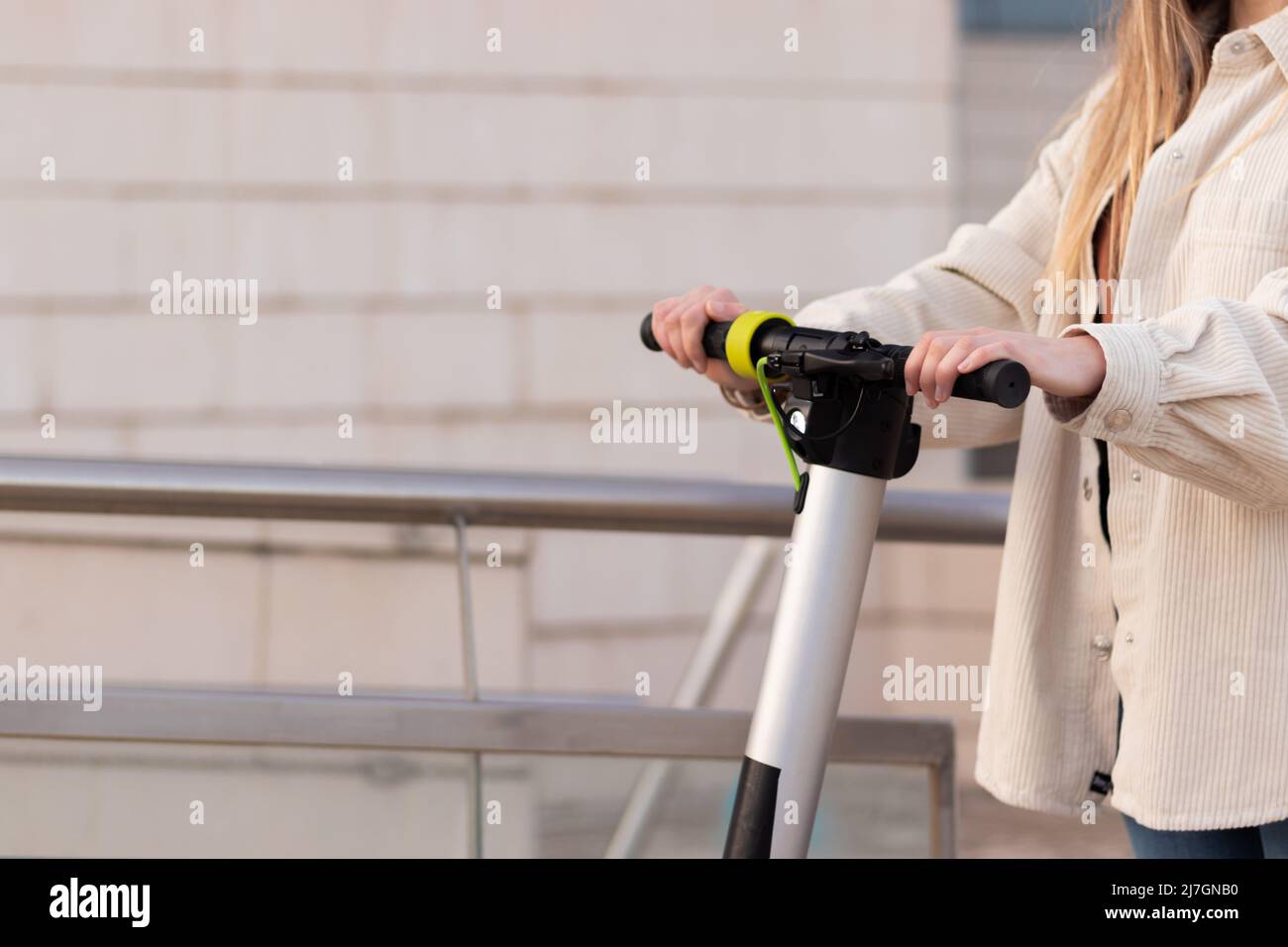 Close up view of unrecognizable young woman holding electric scooter ...