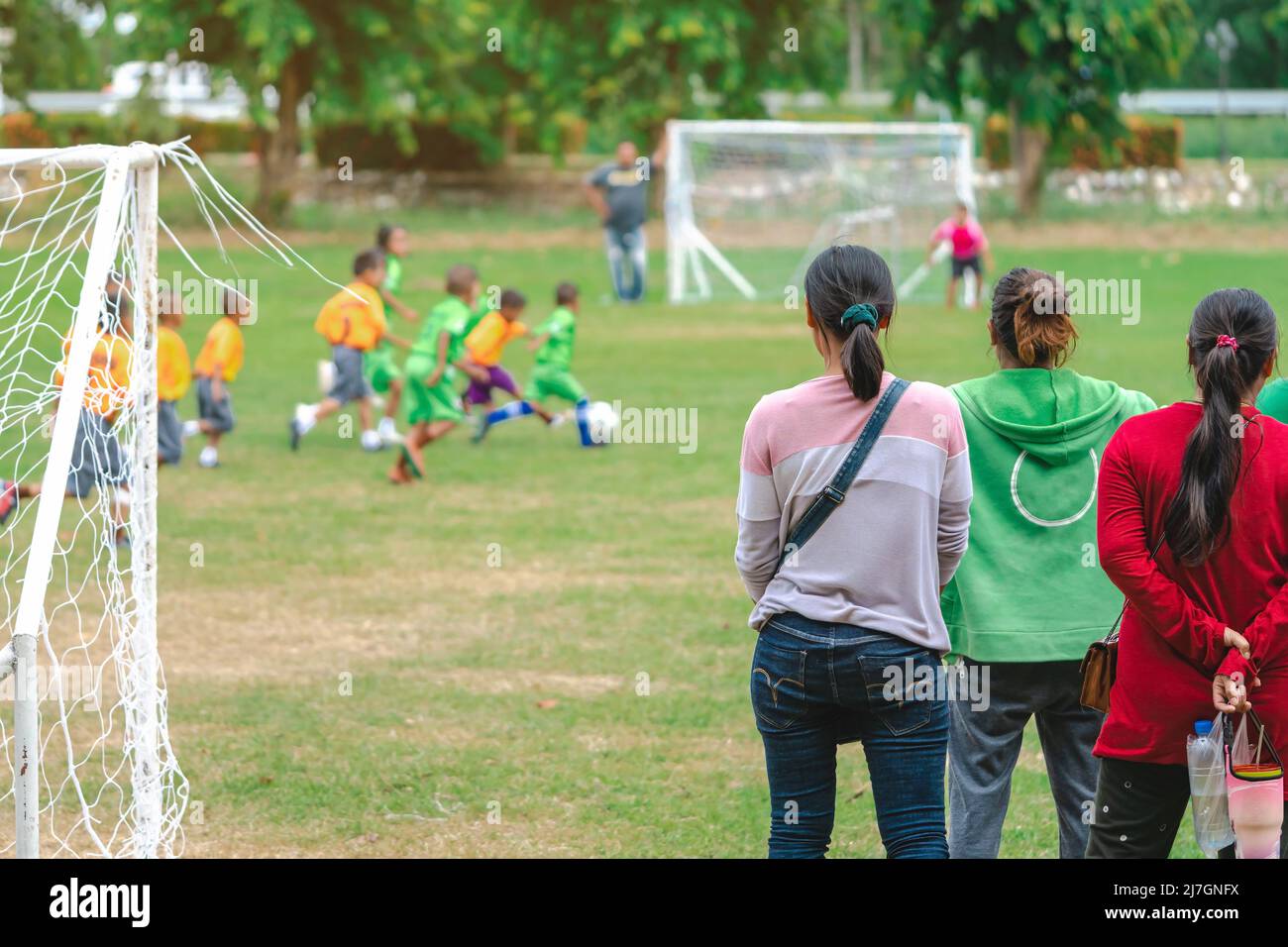 Back view of Moms watch and cheering their sons playing football in ...