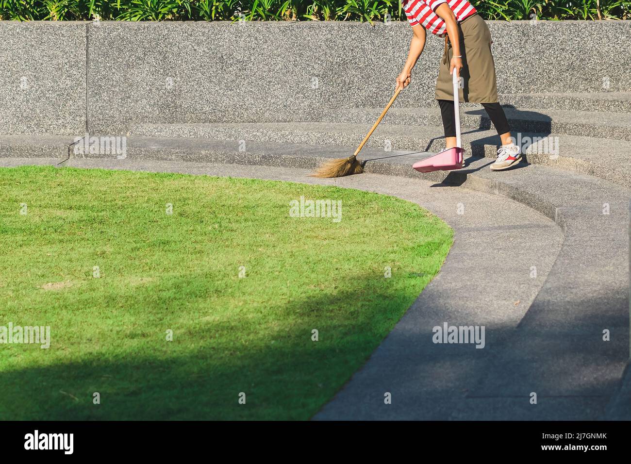 Female Worker Sweeping Yard With Broom Tool And Dustpan In Ornamental