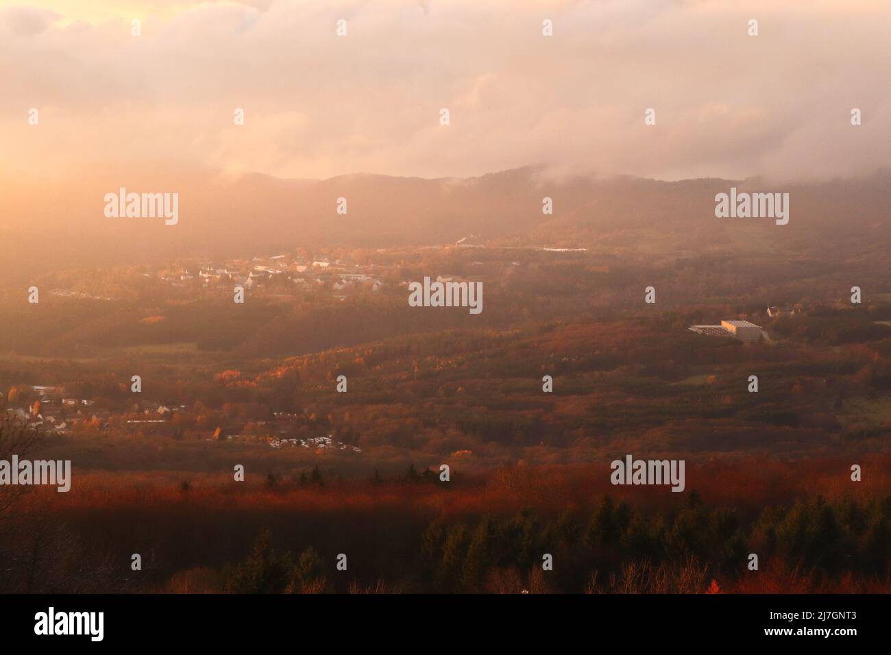 Orange light from sunset over a small town in the Rhon mountains on a ...