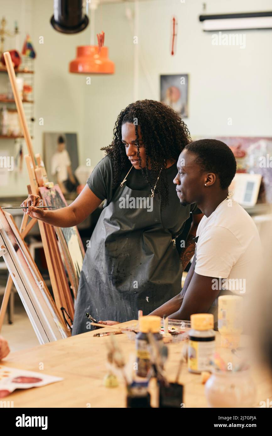 Female tutor teaching painting to young student in art class Stock ...