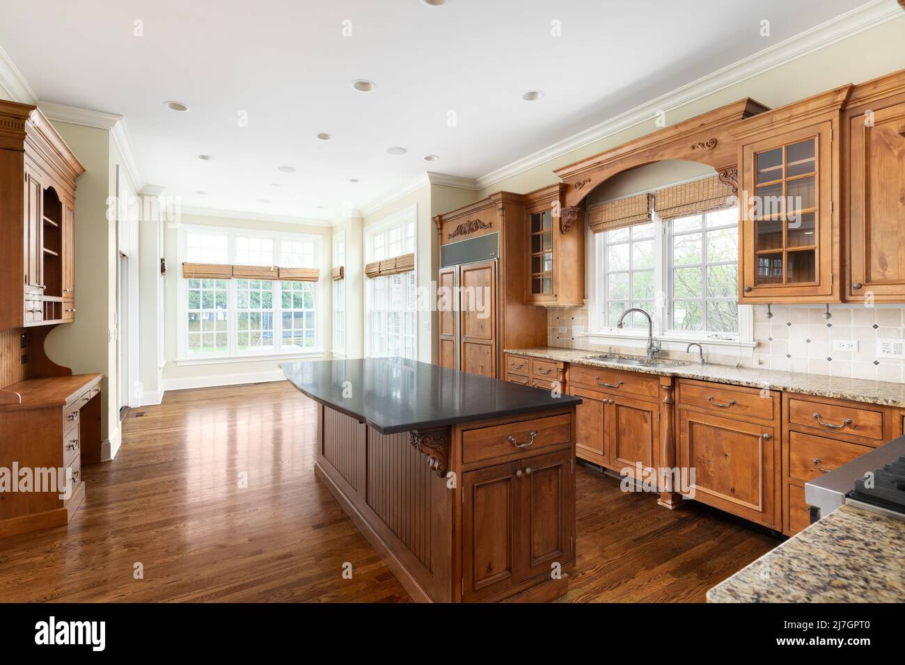 A luxurious wood kitchen with a large island, stainless steels ...