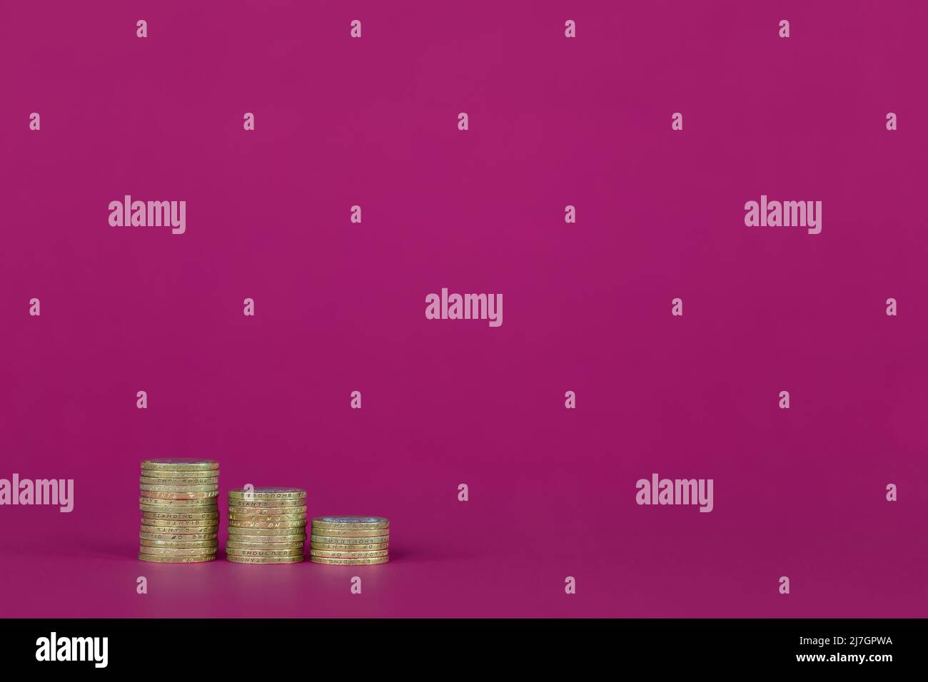 UK British Pound Sterling GBP stacks of gold coloured coins on a bright ...