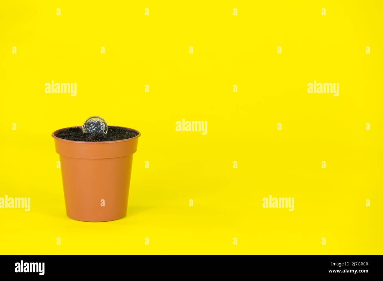 UK Pound coin in a typical terracotta plant pot - saving money concept ...