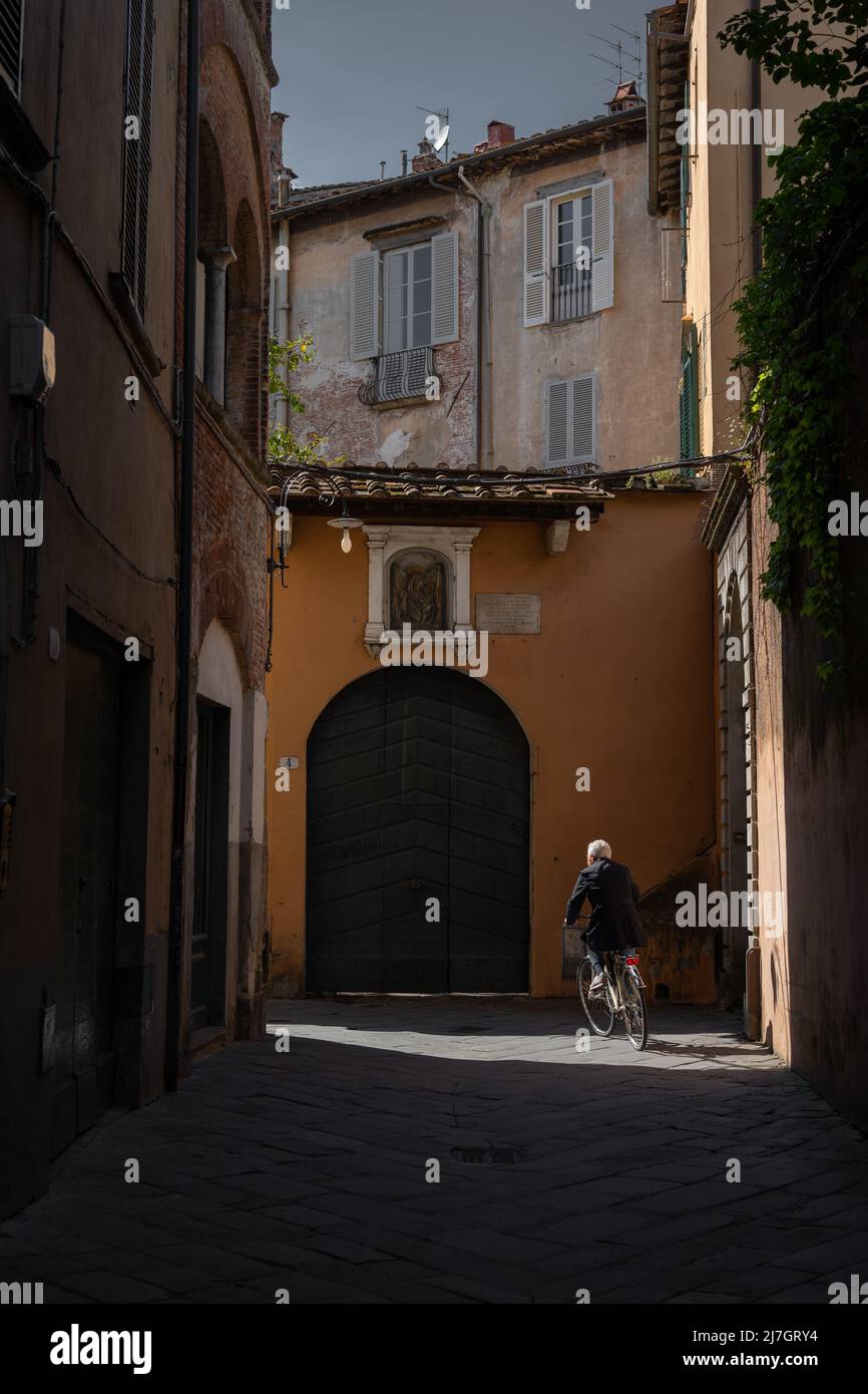 Cyclist rounds a corner in a back alley of Lucca Stock Photo - Alamy