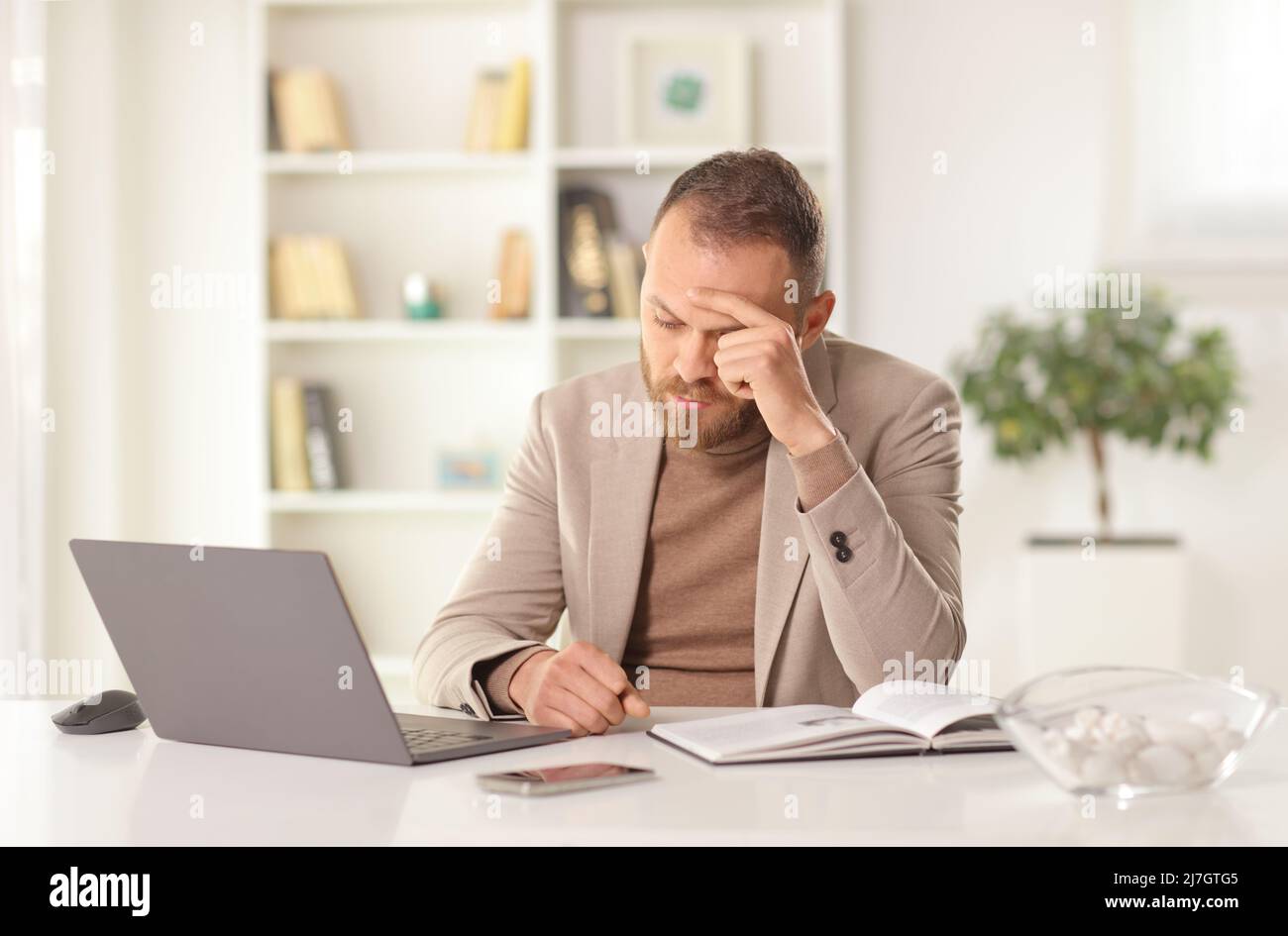 Tired young man working from home with a laptop computer sitting and ...