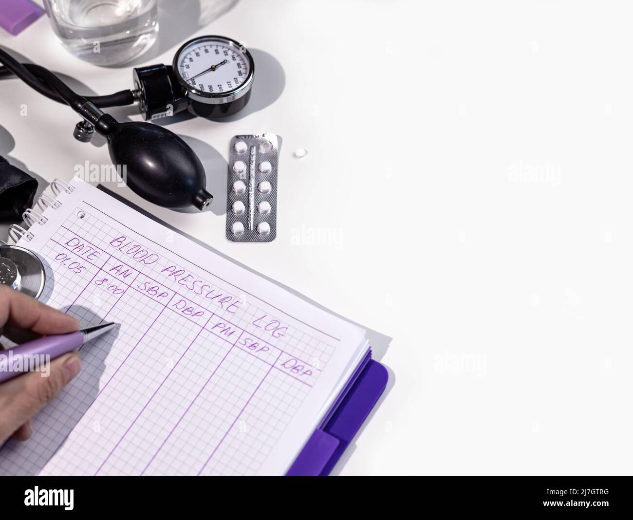 Blood pressure log with pen and Blood pressure monitor on white table ...