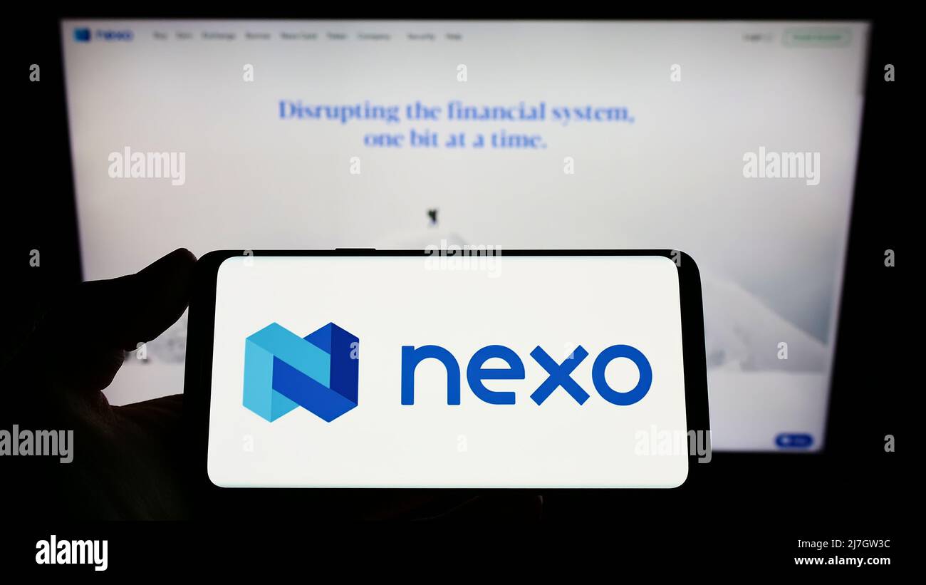 Person holding mobile phone with logo of British digital assets company Nexo (nexo.io) on screen ...
