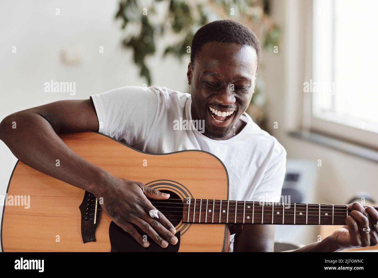 Happy male artist singing while practicing guitar in classroom Stock ...