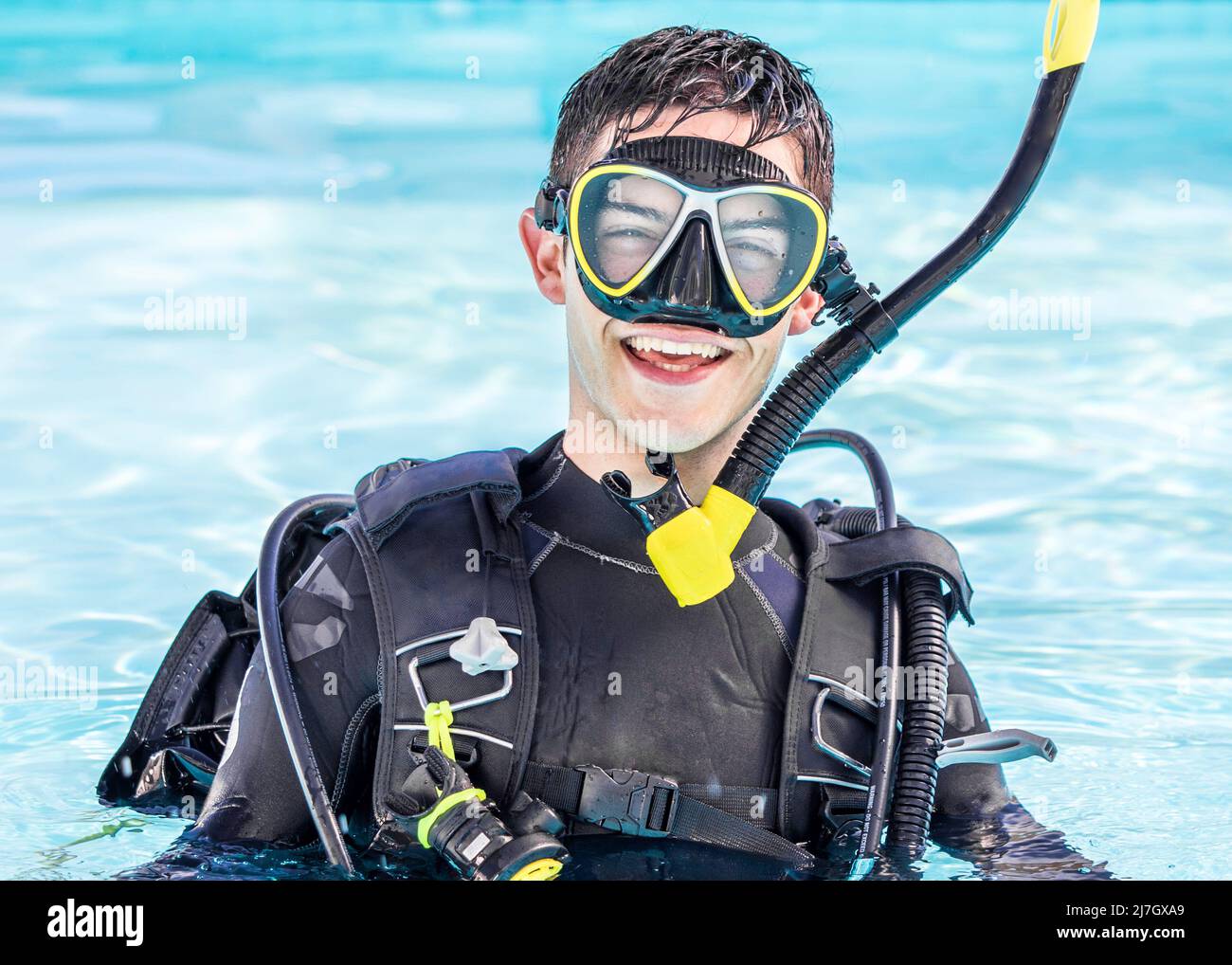 A happy young man with scuba gear on in a pool smiling at the camera ...