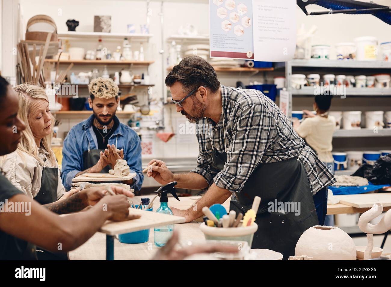 Mature instructor with work tool teaching student in art class Stock ...