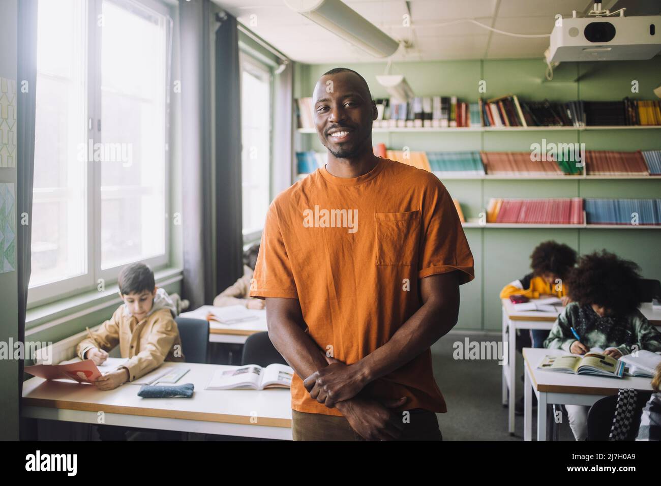 Portrait of confident male teacher with students in classroom Stock ...