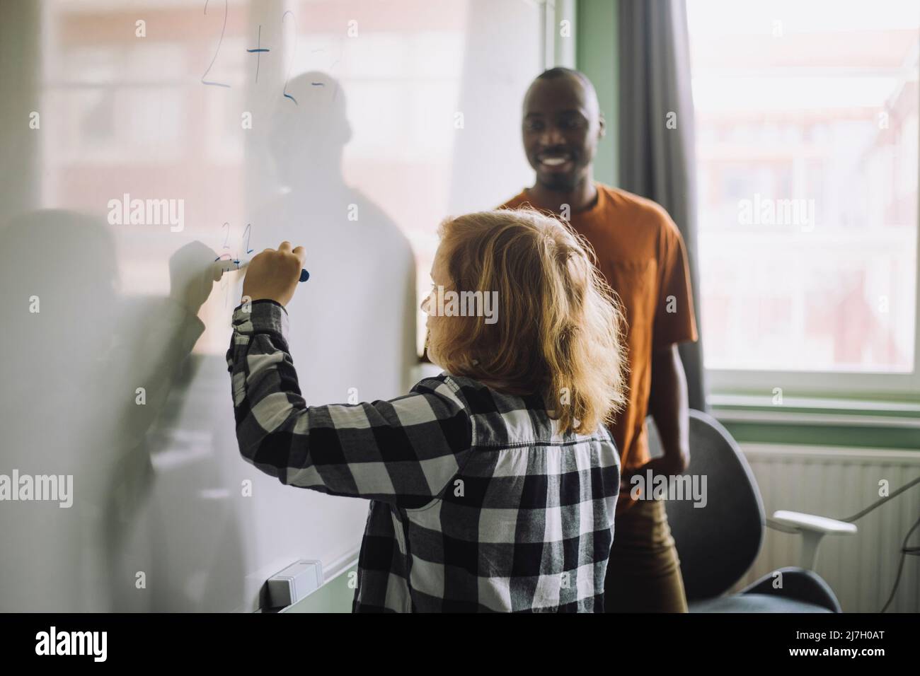 Side view of boy solving math problem on whiteboard in classroom Stock ...