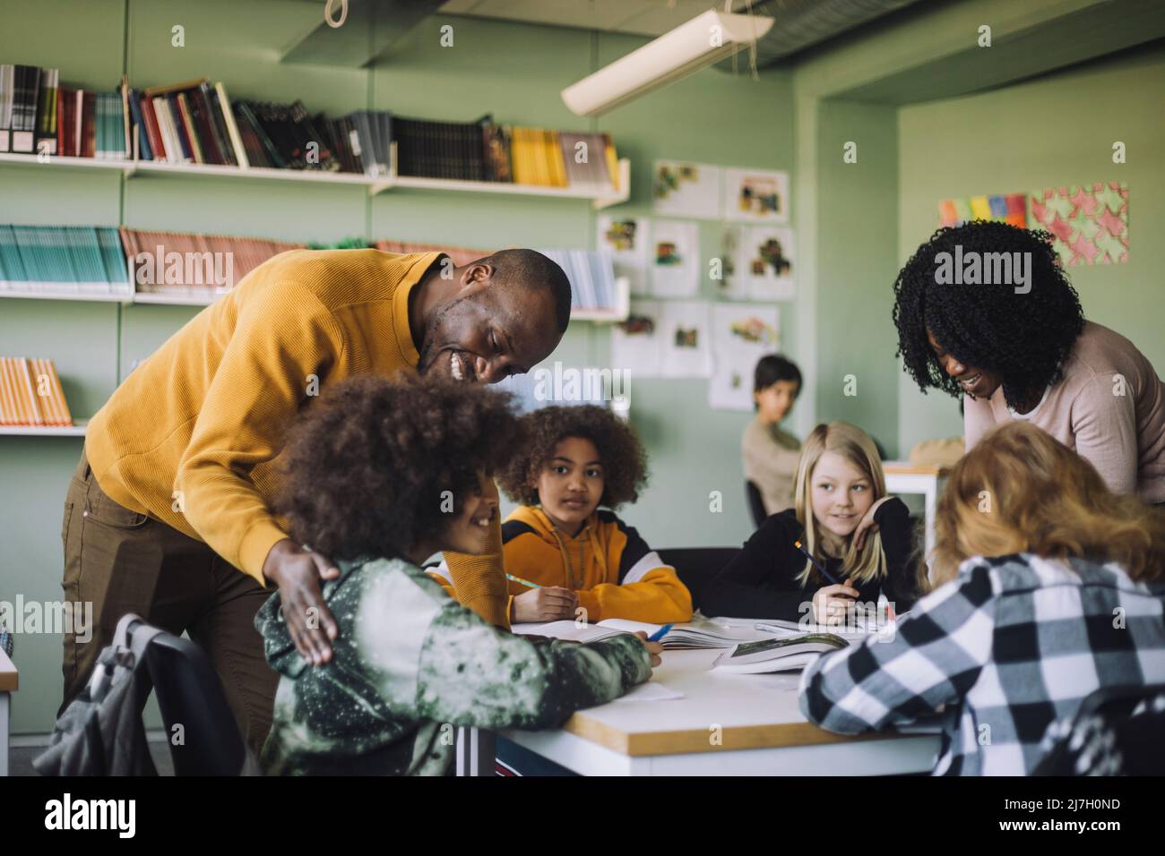 Teachers assisting students while studying in classroom at school Stock ...