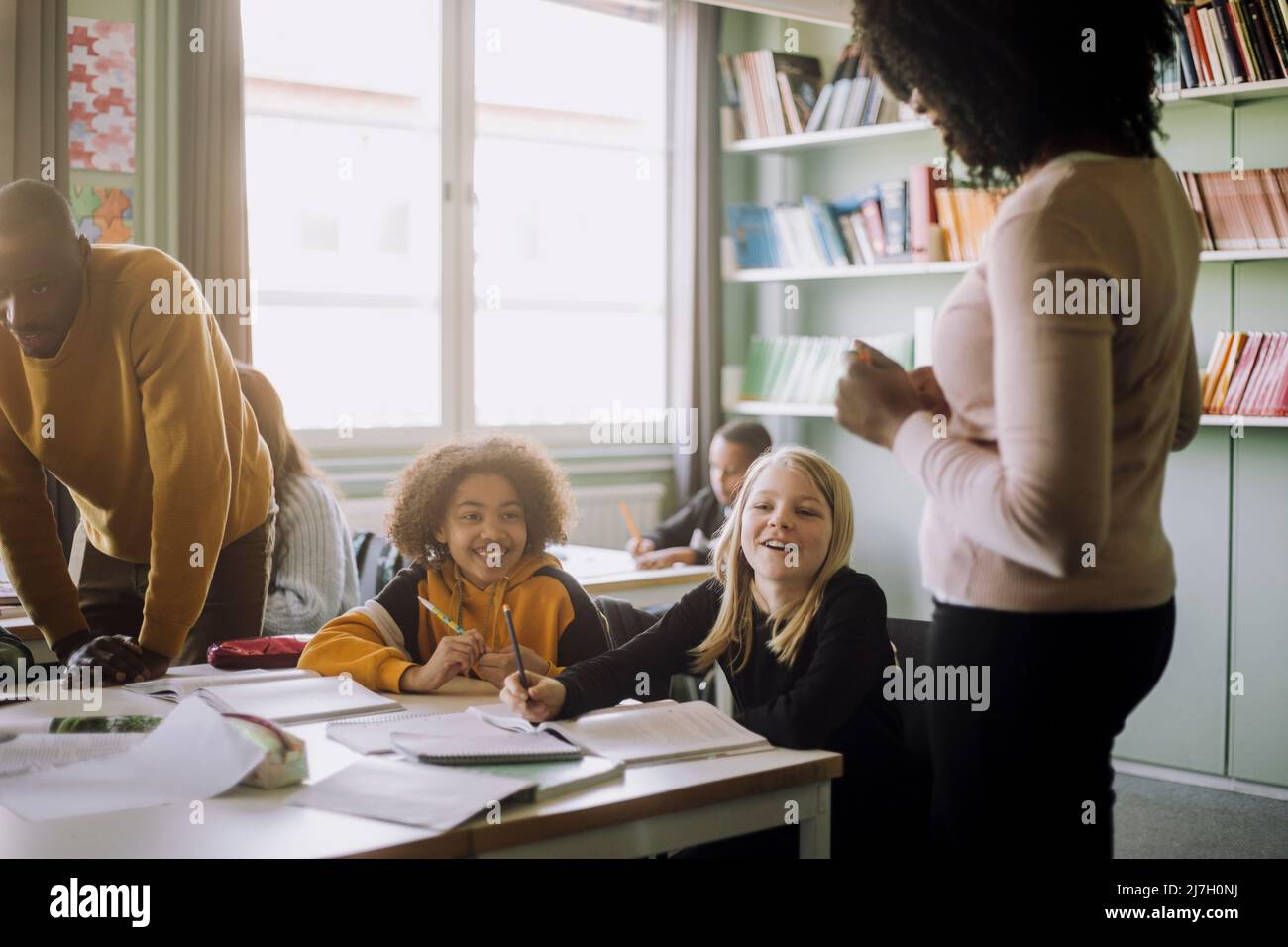 Smiling pupils interacting with teacher in classroom at school Stock ...