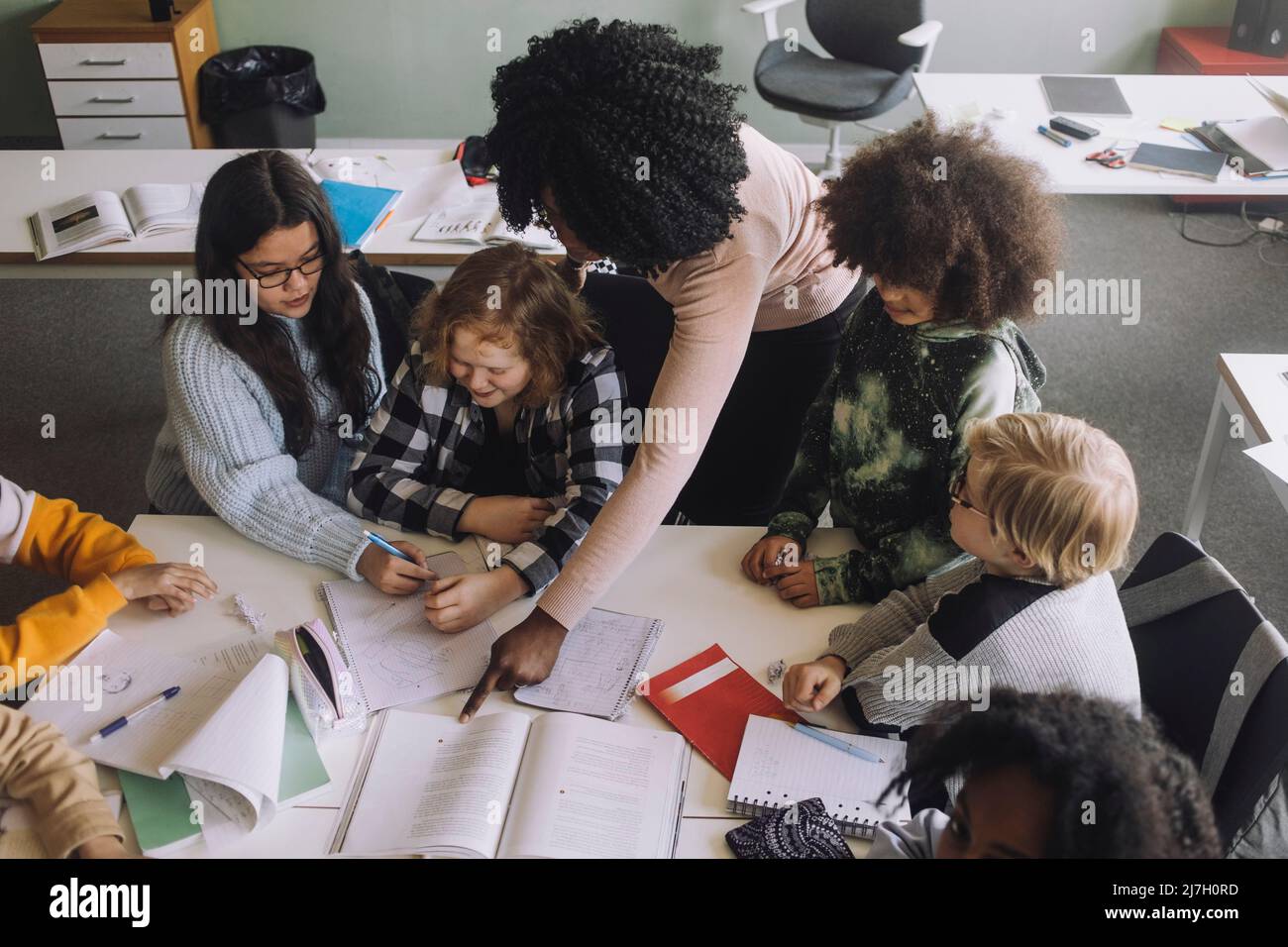 Teacher pointing at book while teaching in classroom Stock Photo - Alamy