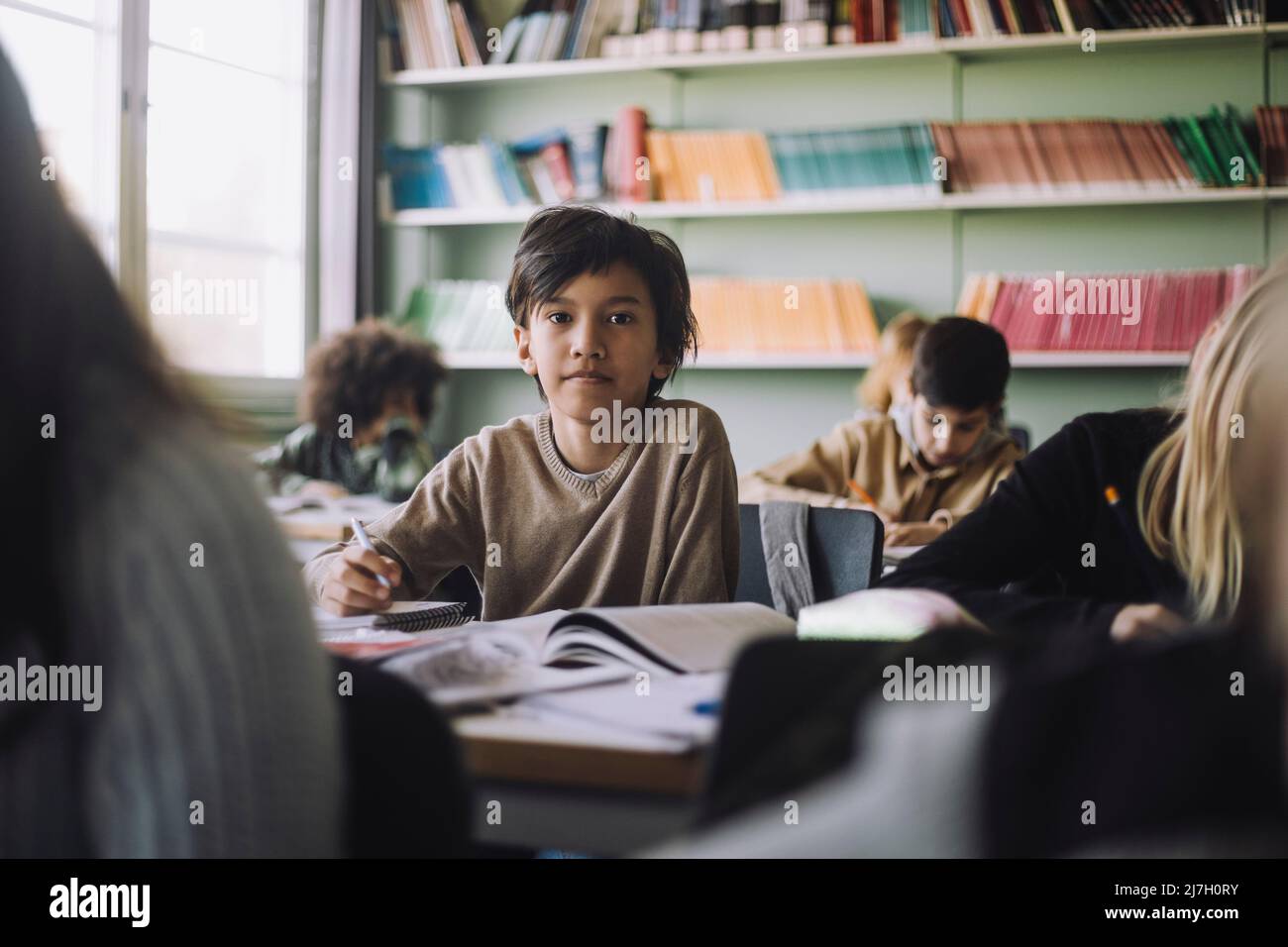 Portrait of boy sitting on desk in classroom at school Stock Photo - Alamy