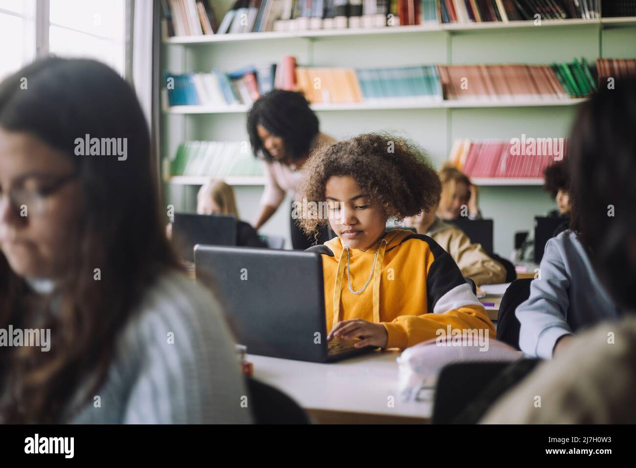 Girl using laptop at desk while studying in classroom Stock Photo - Alamy
