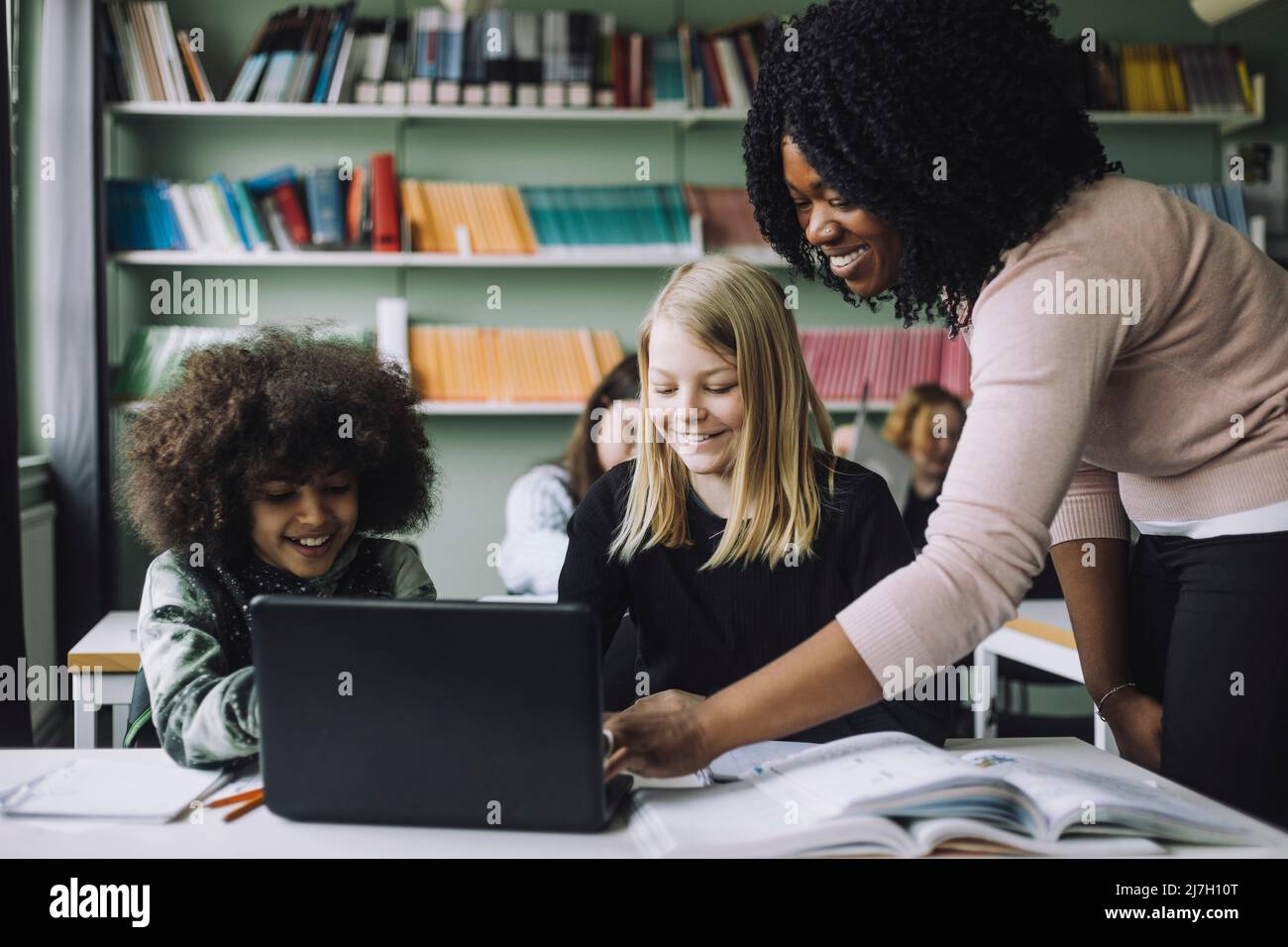 Happy multiracial students and teacher doing e-learning in classroom ...
