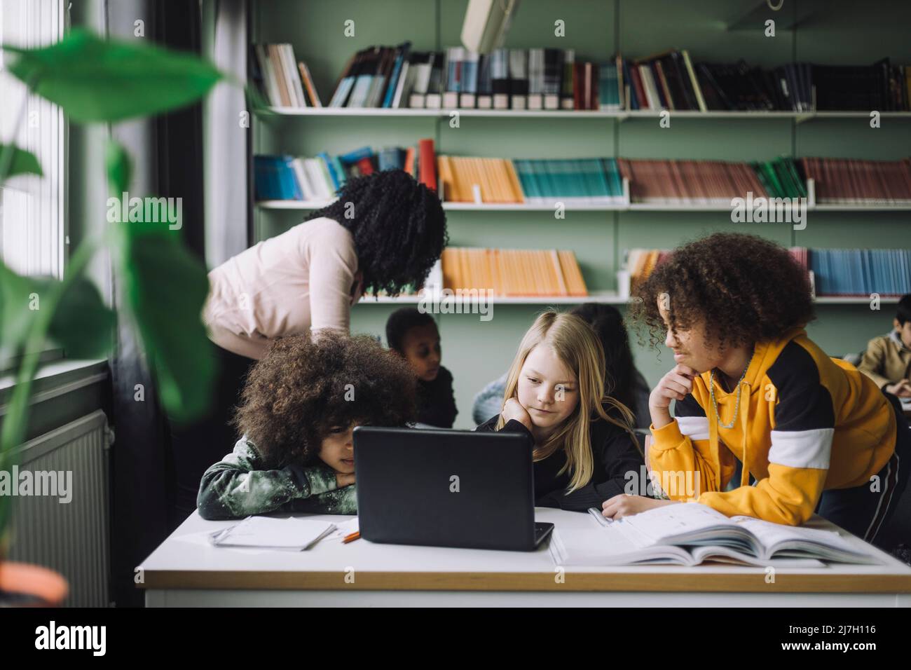 Multiracial students watching laptop while studying in classroom Stock ...