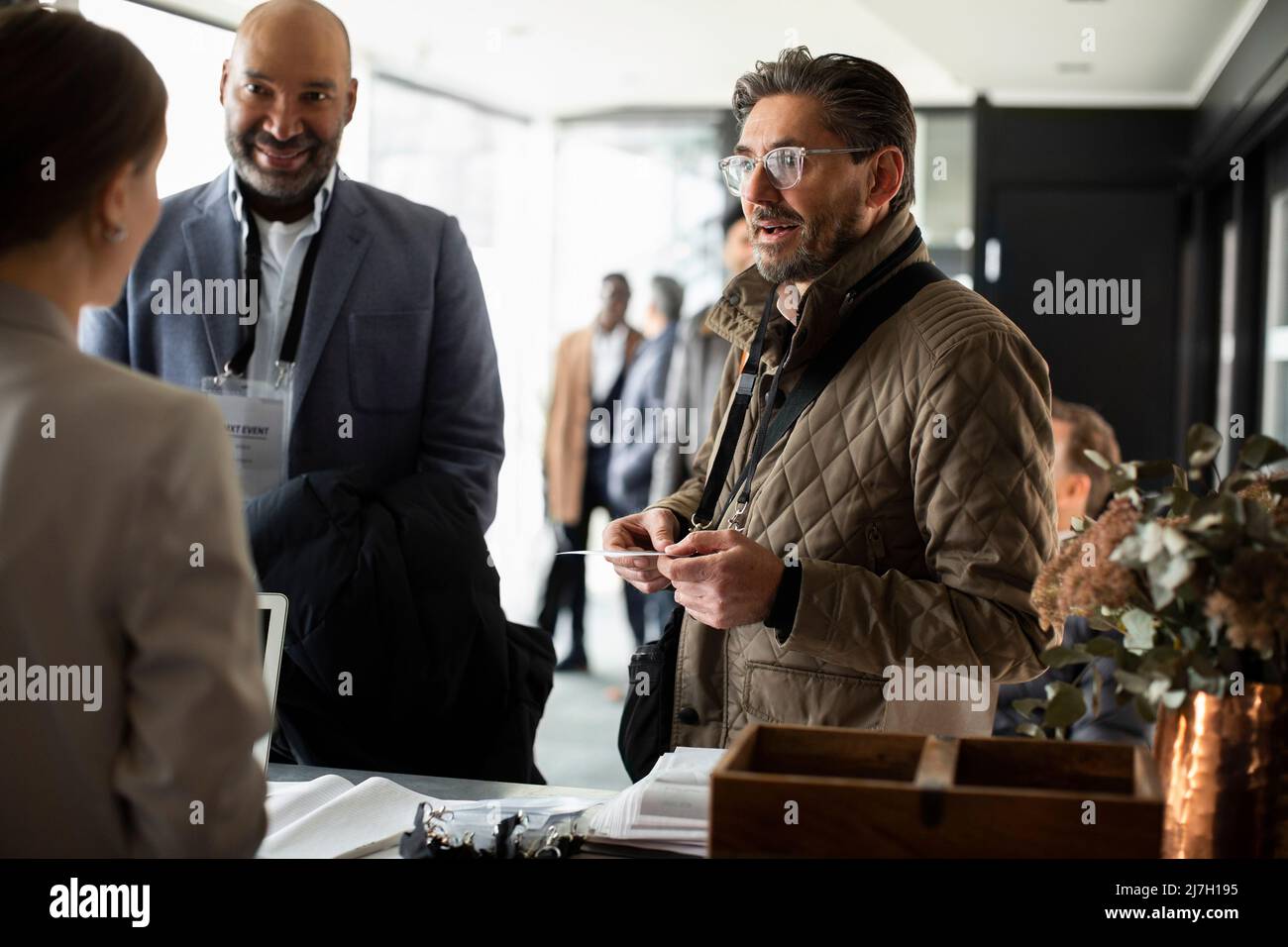 Businessman talking to receptionist at registering counter in ...