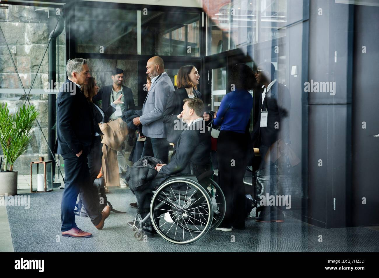 Corporate delegates discussing in corridor of conference center during ...