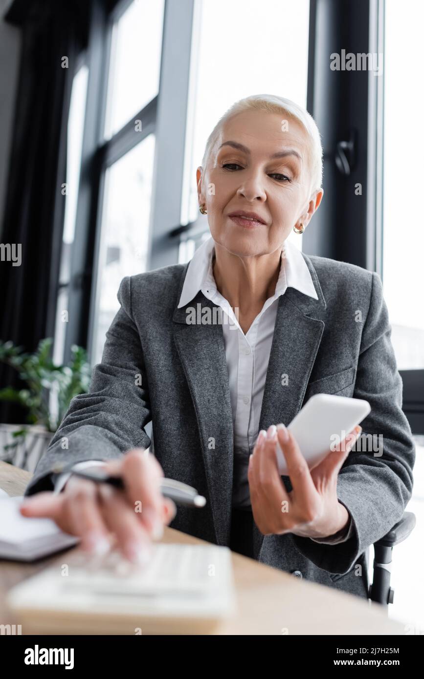 accountant holding mobile phone while using blurred calculator in ...