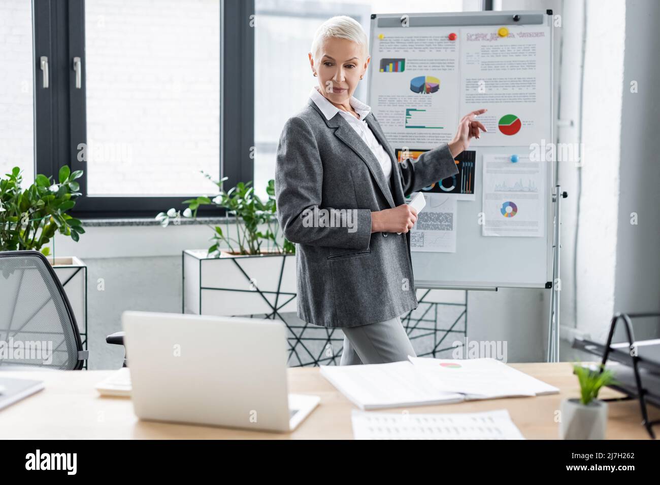senior economist pointing at flip chart with graphs during video call ...