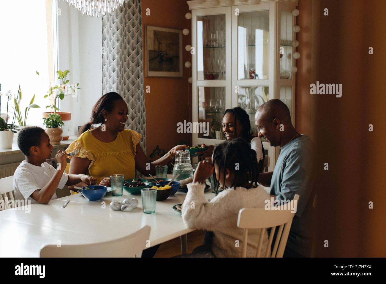 Family having lunch together while sitting at dining table Stock Photo ...