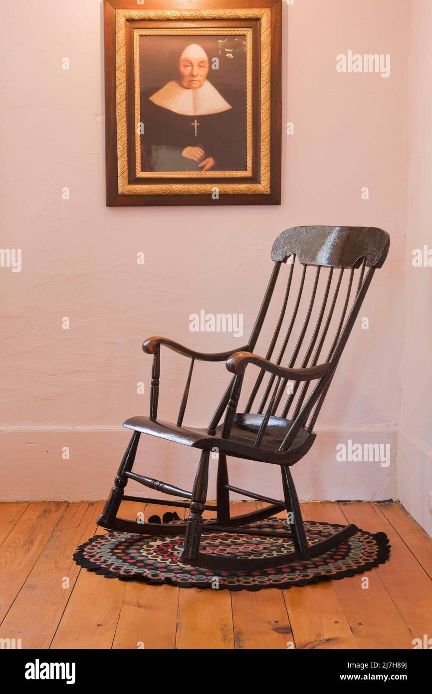 Antique rocking chair on round weaved rug and religious portrait on ...