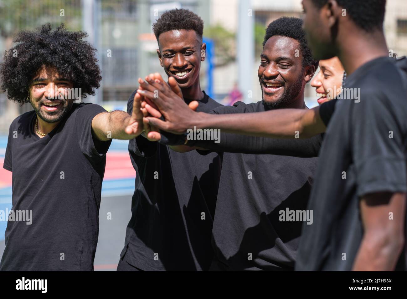 Group of friends joining hands on basketball court Stock Photo - Alamy