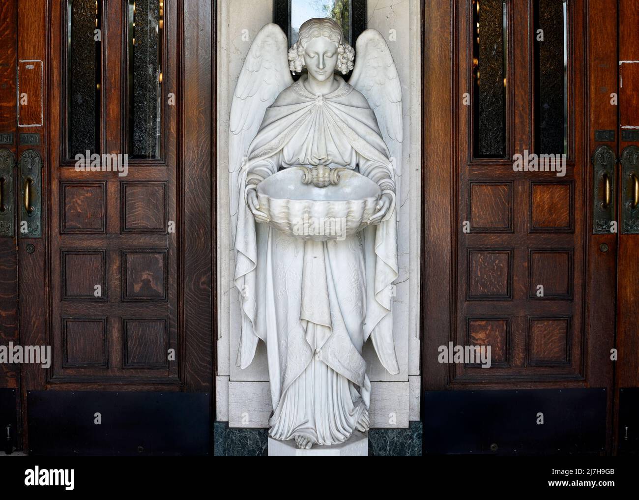 A marble holy water font in the form of an angel at the entrance to the ...