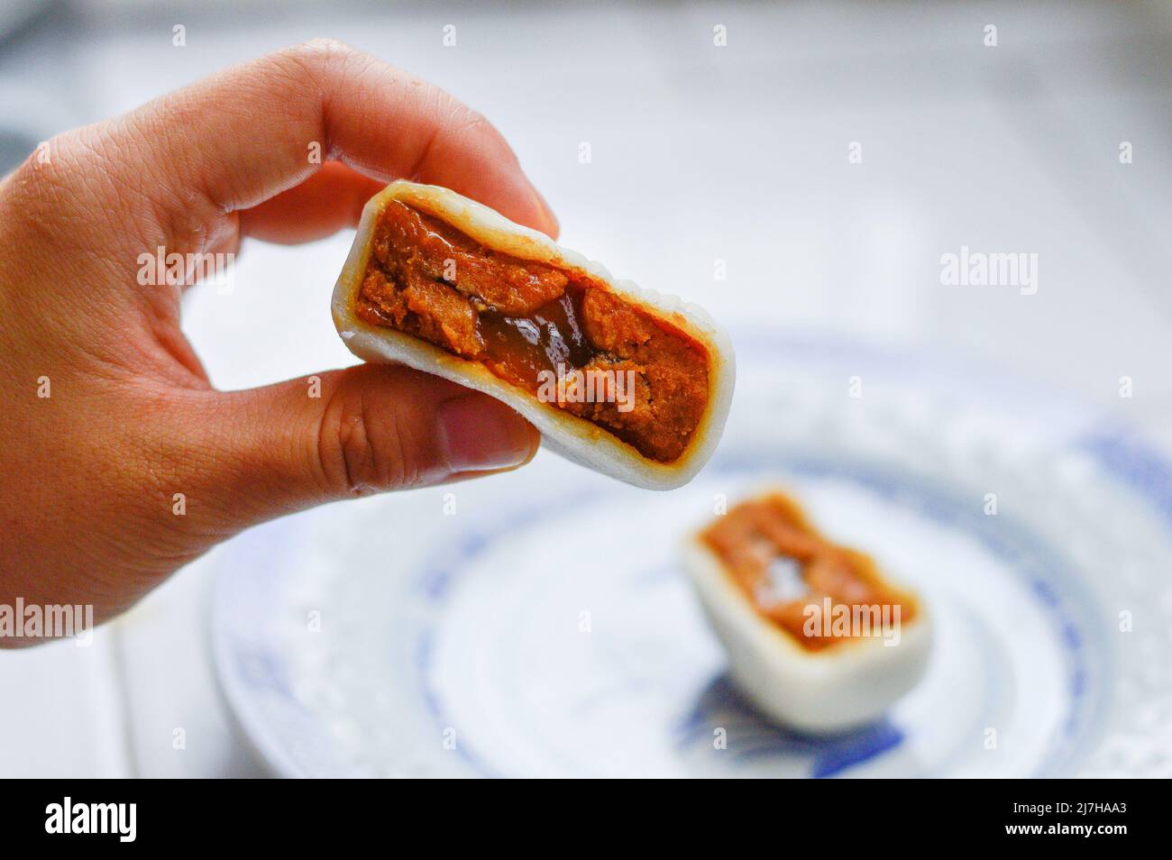Hand holding a half-opened Chinese snowy moon cake, showing yolk ...
