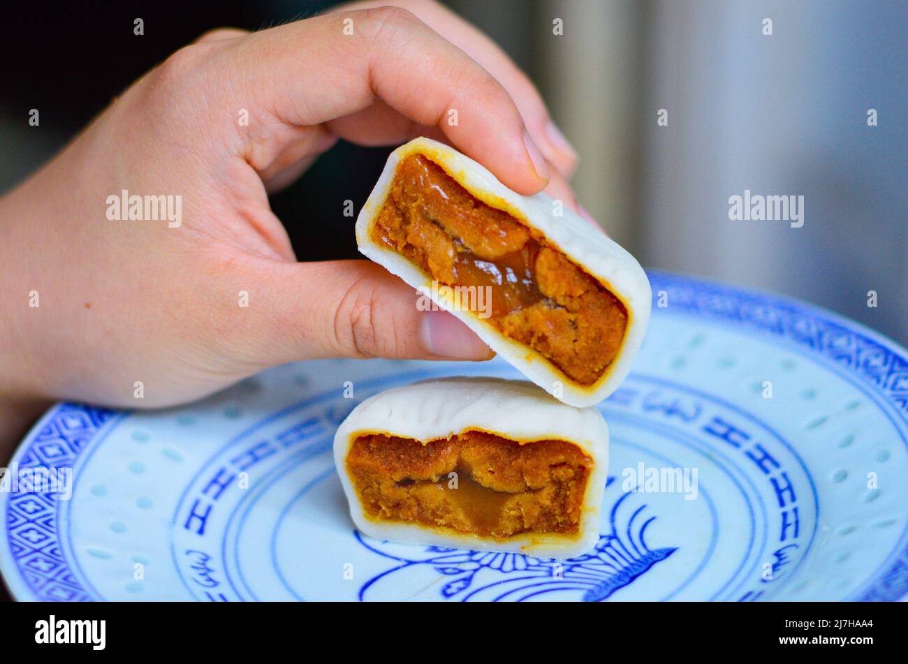 Hand holding a half-opened Chinese snowy moon cake, showing yolk ...