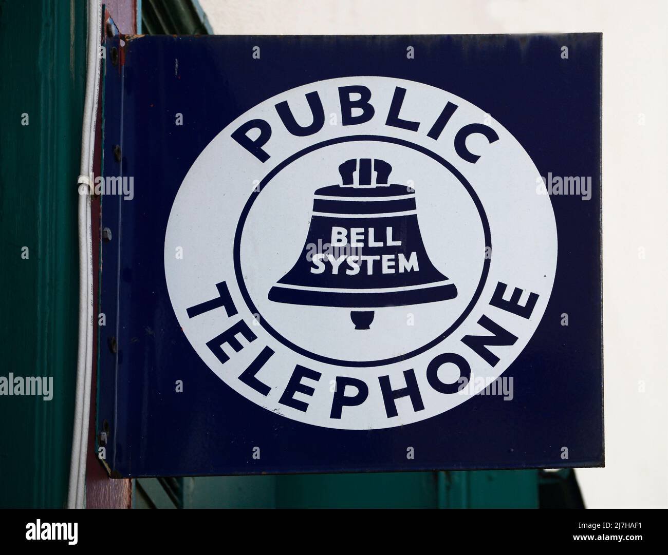 A vintage 1950s Bell System public telephone sign hangs on the side of ...