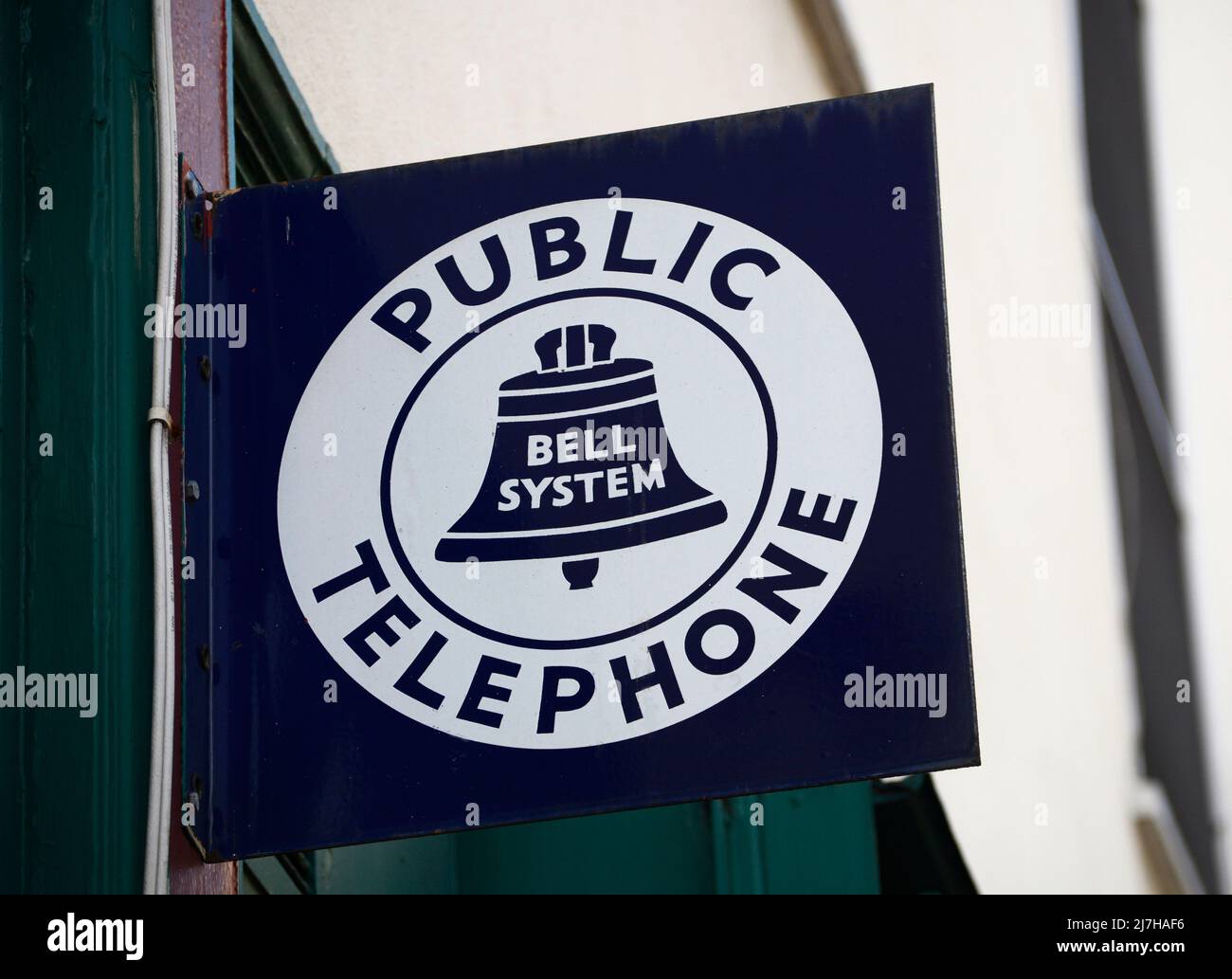 A vintage 1950s Bell System public telephone sign hangs on the side of ...