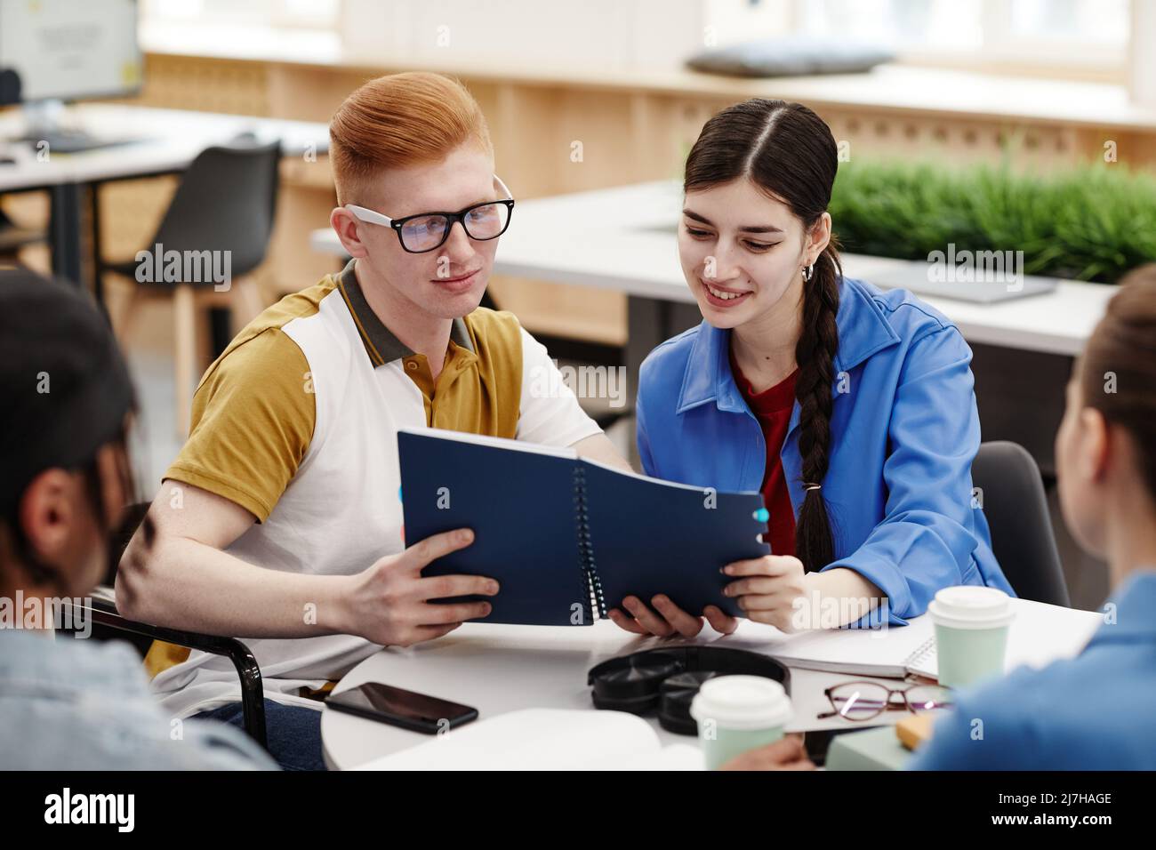 Vibrant shot of two smiling college students reading notes during group ...
