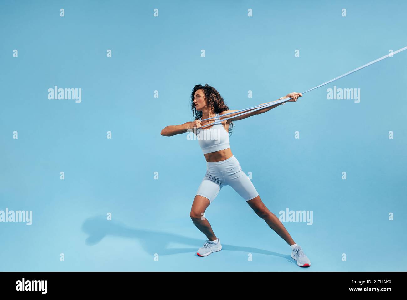 Muscular woman pulling resistance band. Young female in sportswear ...