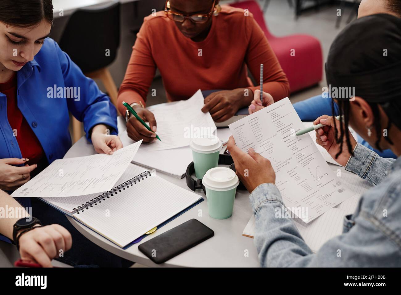 High angle view at diverse group of college students reading notes ...