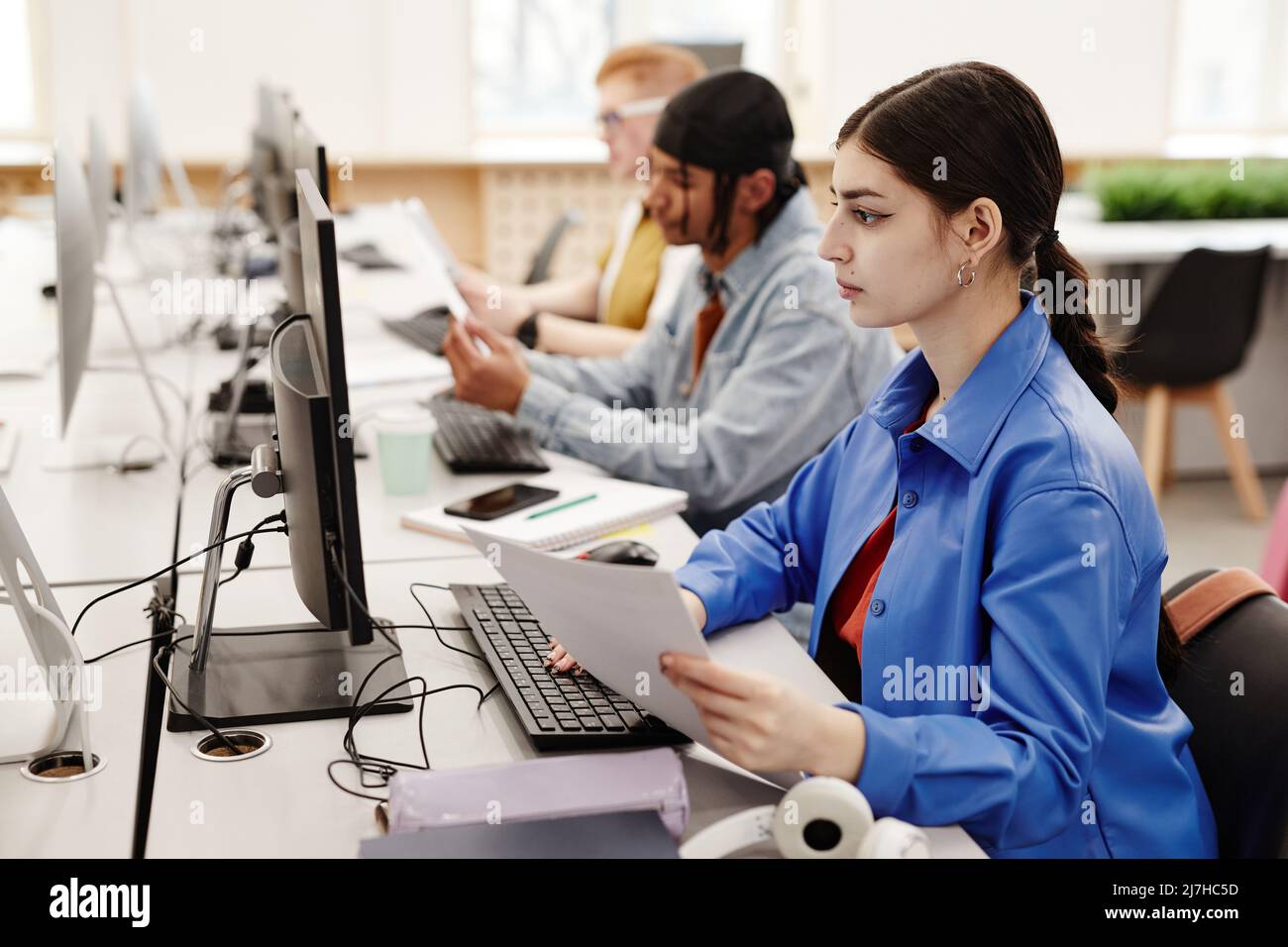 Side view portrait of ethnic young woman using computer in college ...