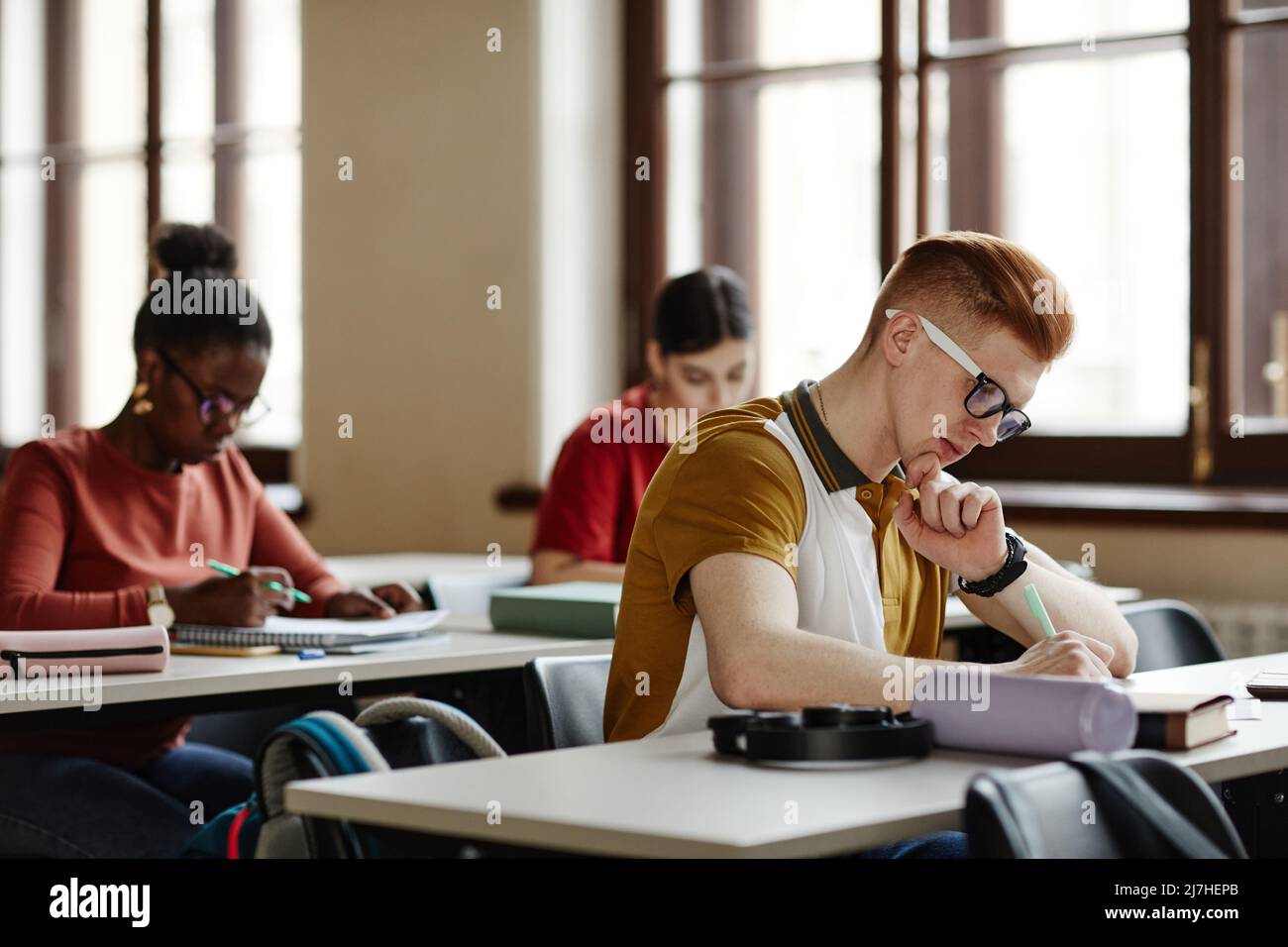 Side view portrait of red haired young man studying at school or ...