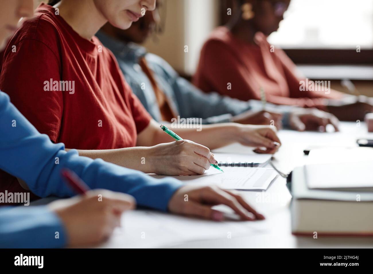 Side view close up of students in row taking notes during lecture in ...