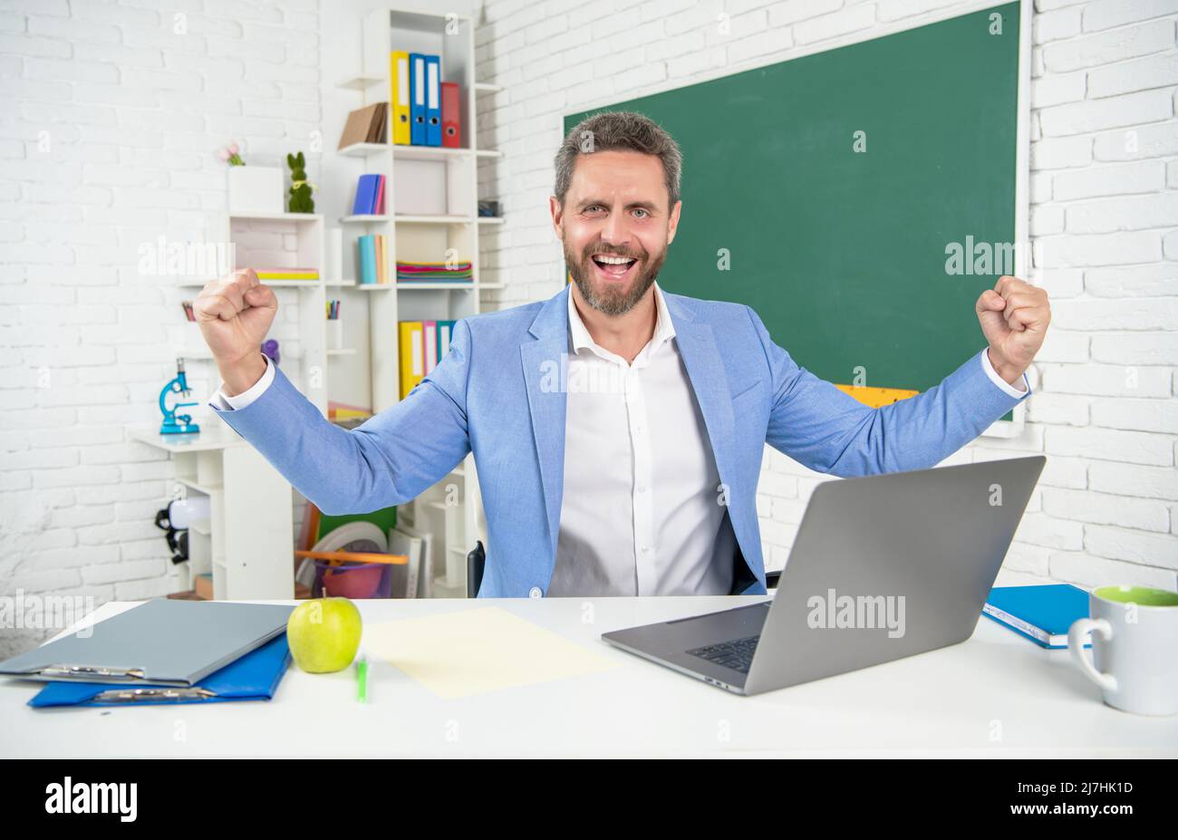 happy glad school teacher in classroom with computer at blackboard ...