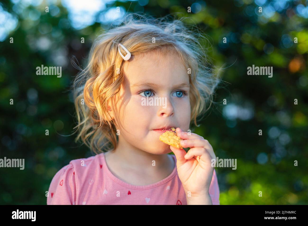 Small child having healthy snack on a sunny summer day outdoors. Little ...