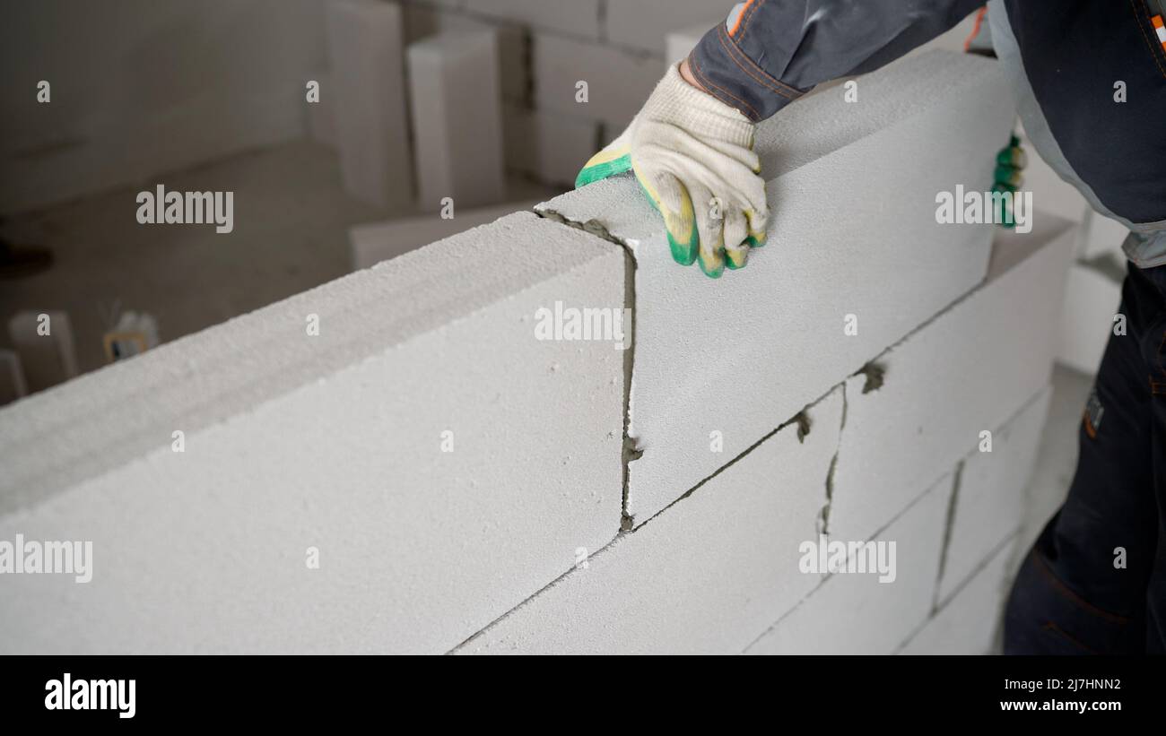 A worker builds a wall from a cellular block. Close-up of a builder's ...